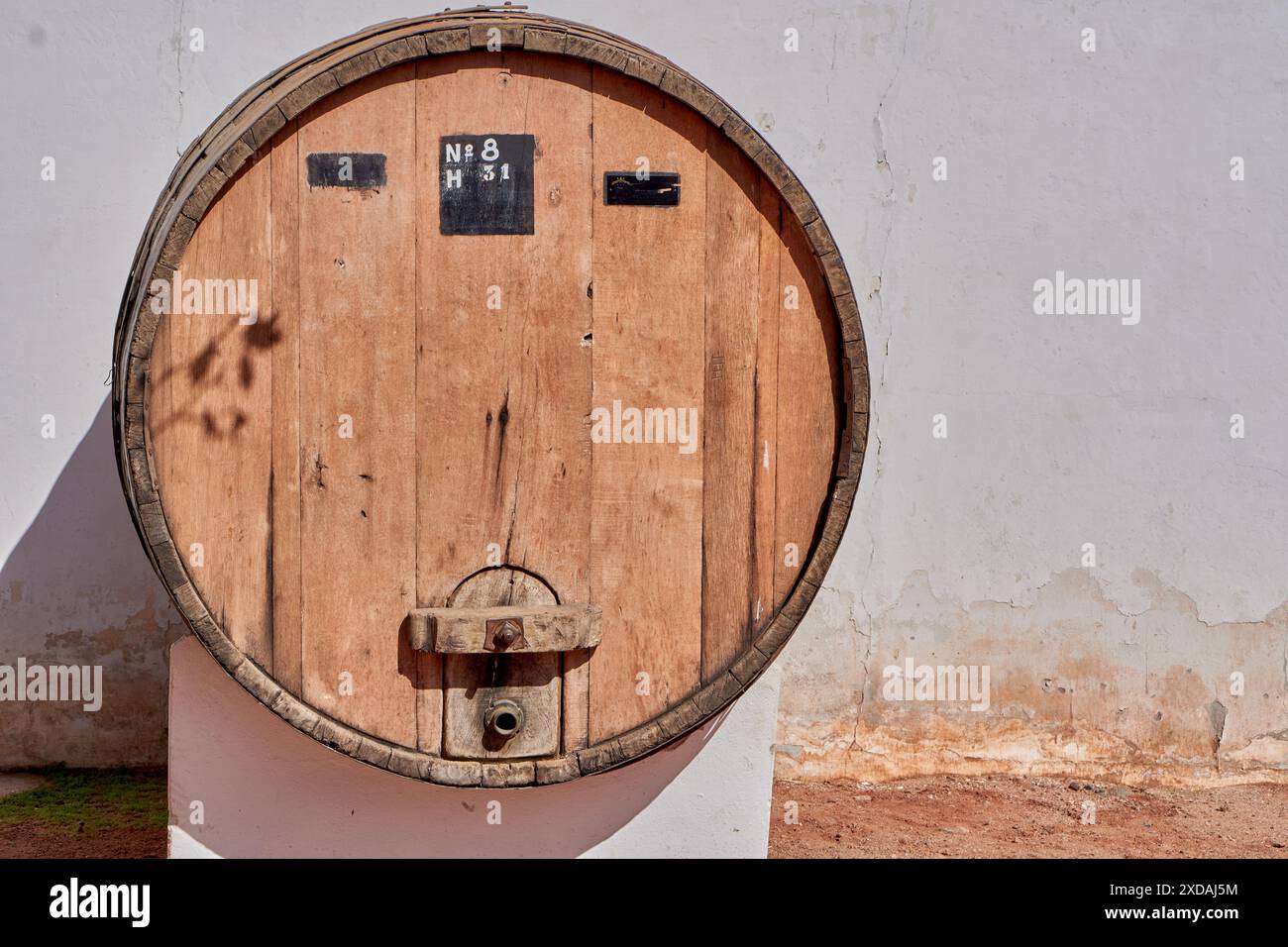 Oak barrel front embedded in an old white wall outdoors in a winery in ...