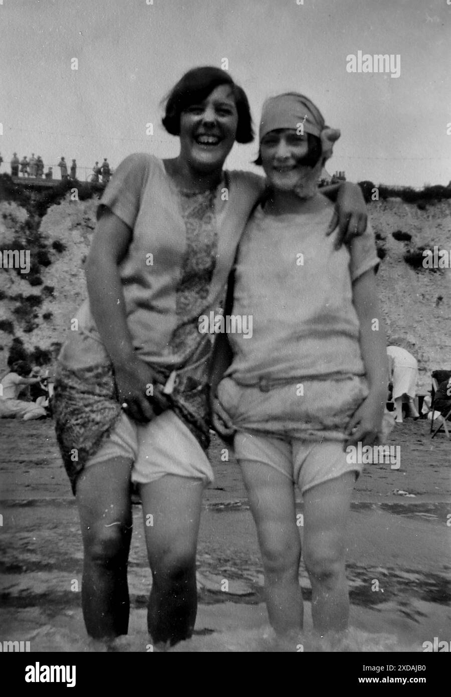 Legs and bloomers, two ladies standing in shallow water, a beach and ...