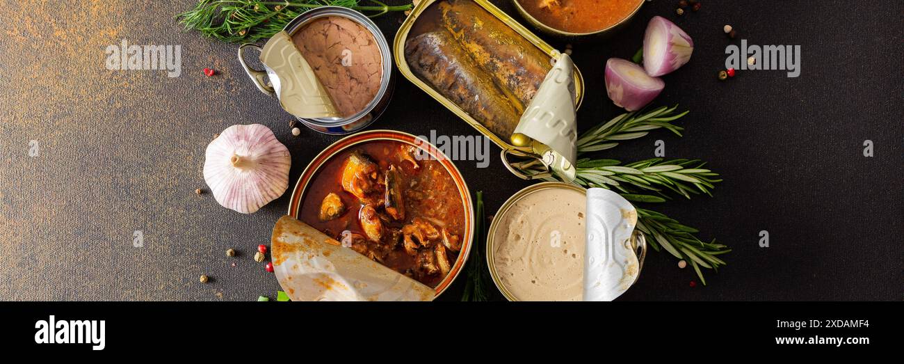Different open tin cans with canned fish among spices and herbs banner ...