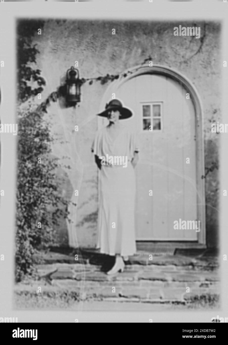 King, Hamilton, Mrs., standing outdoors in front of an arched door ...