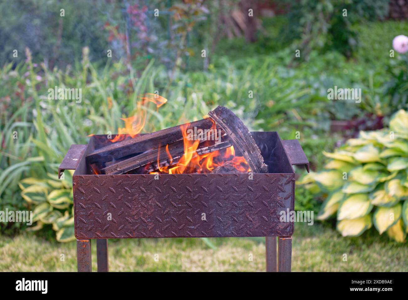 Rustic metal barbecue grill with fire flame. Burning firewood in a ...