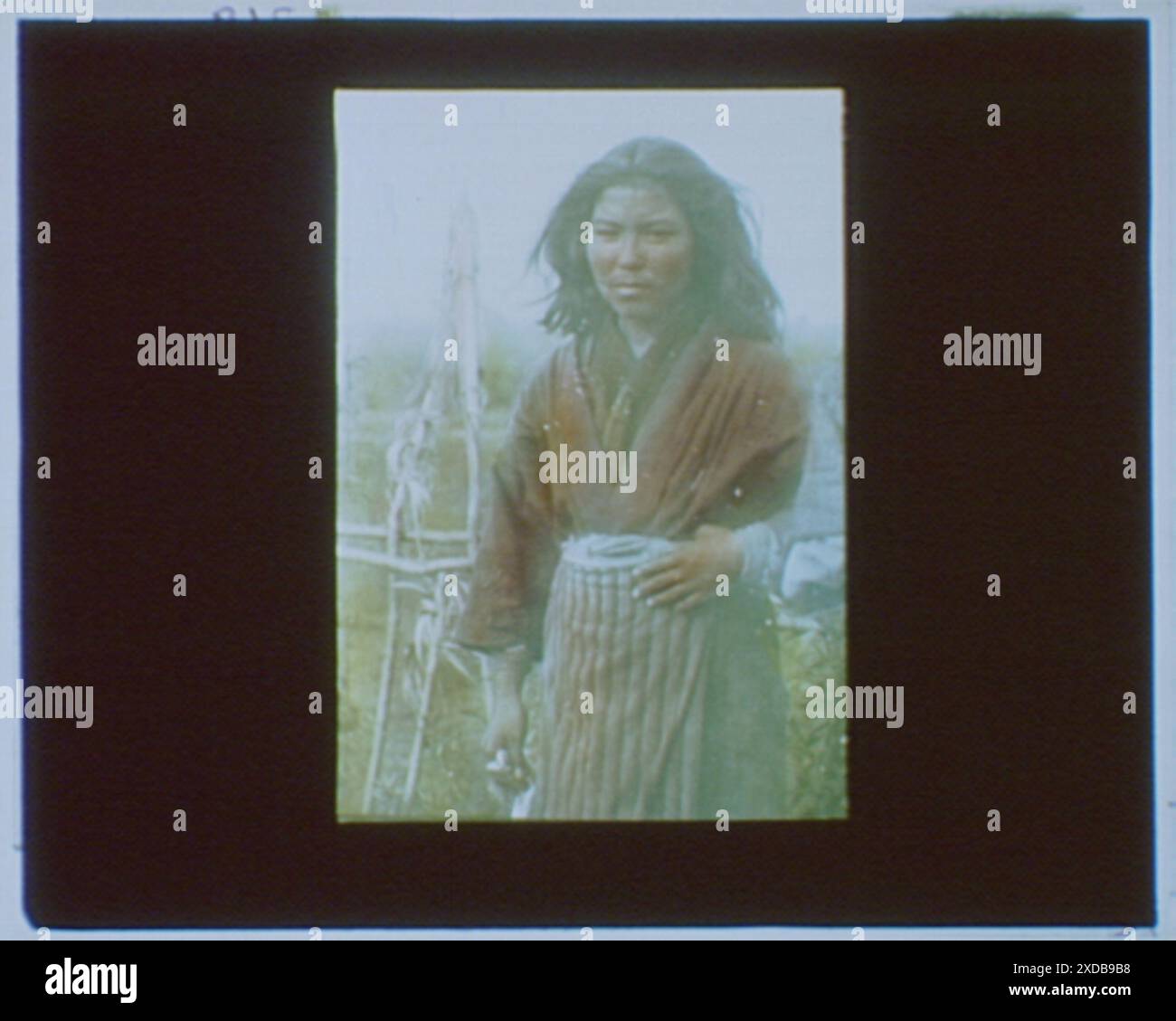 Ainu woman standing outside in front of a pole fence. Genthe photograph ...