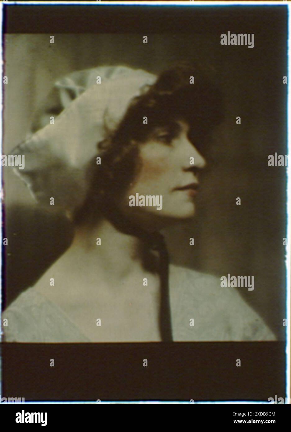 Woman wearing a light-colored hat with a black bow under her chin ...