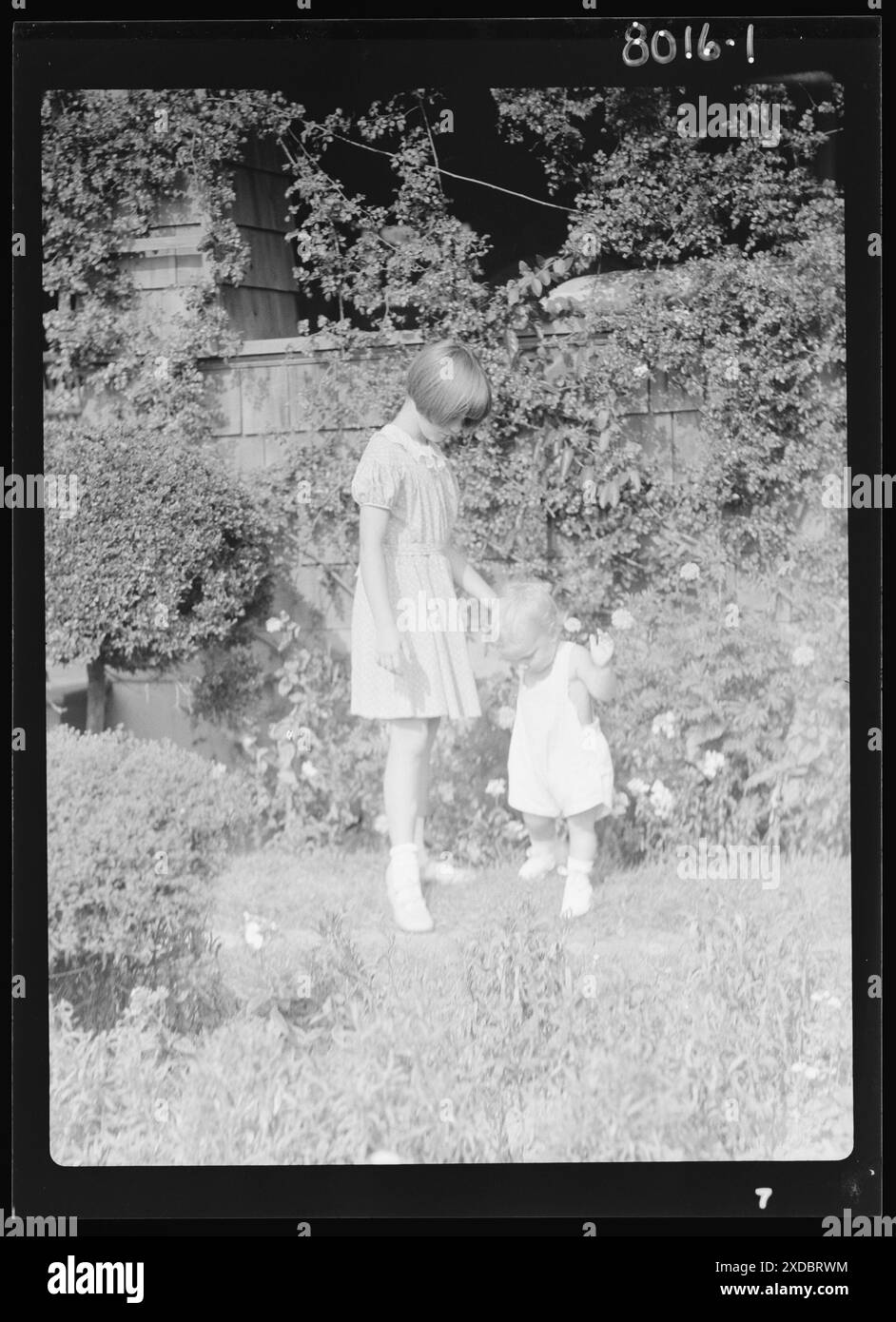 Eustis, George, Mrs., children of, standing outdoors in a garden ...