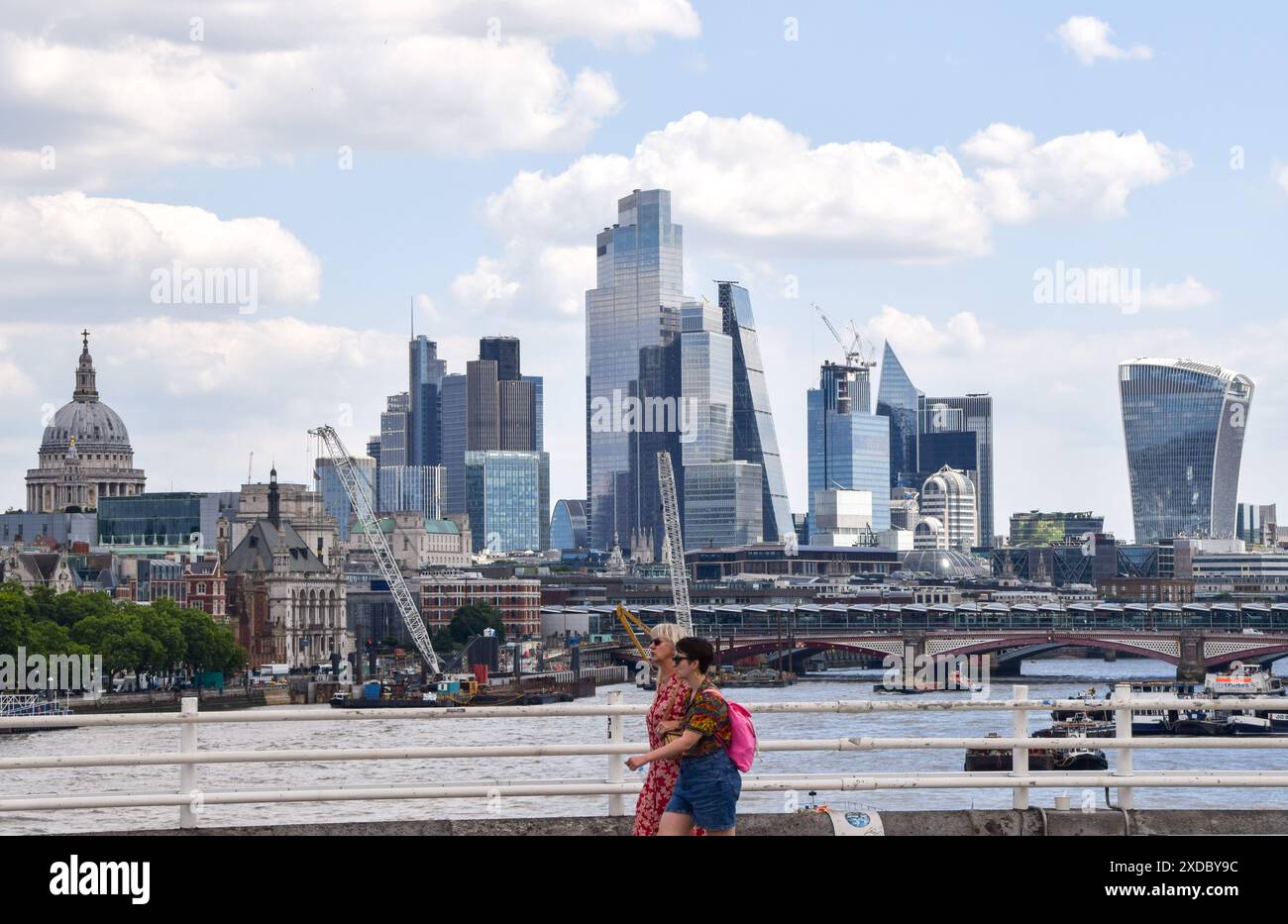 London, UK. 21st June 2024. People walk along Waterloo Bridge past the ...