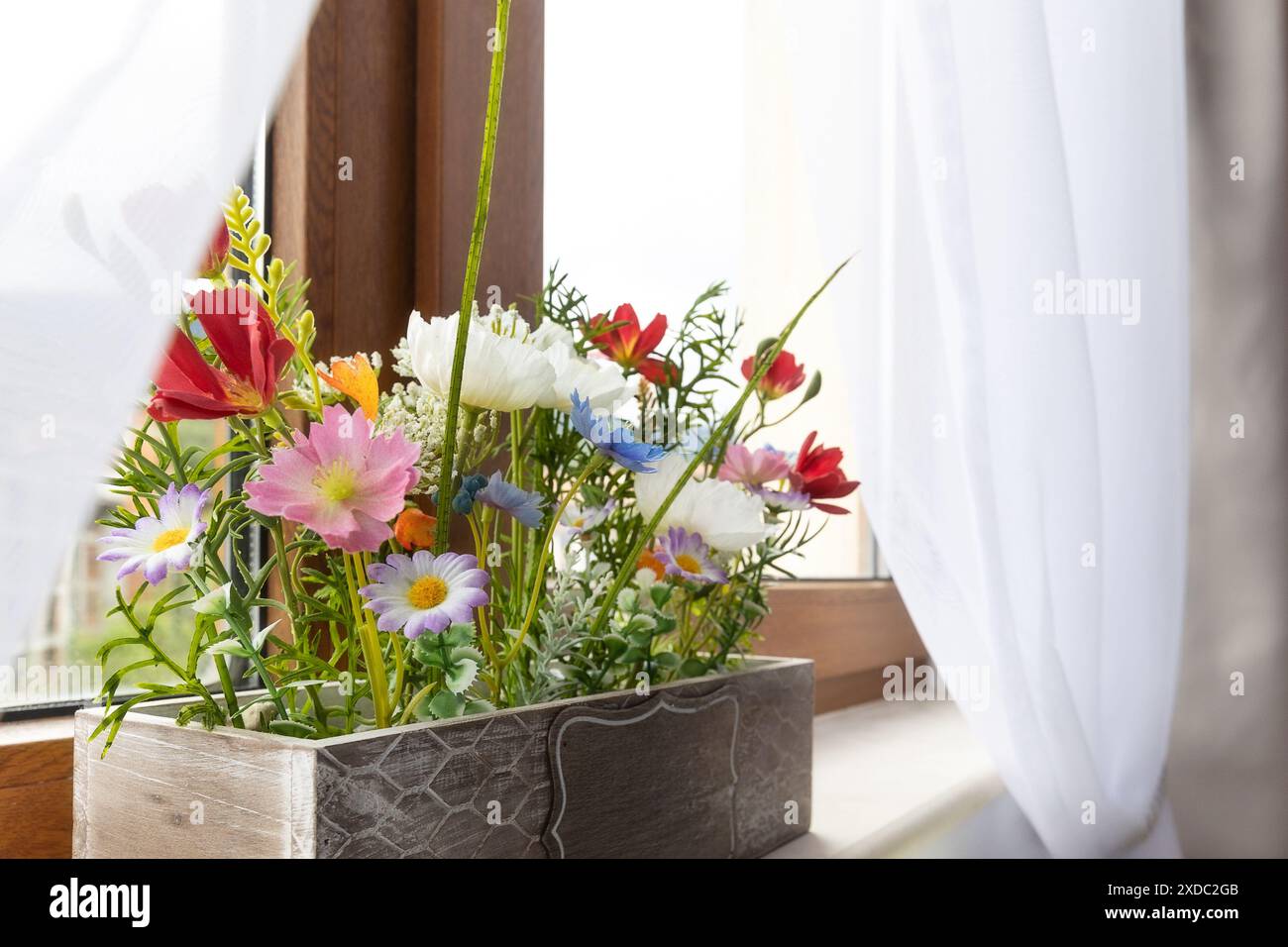 Artificial plant colorful flower in flowerpot on window sill indoors ...