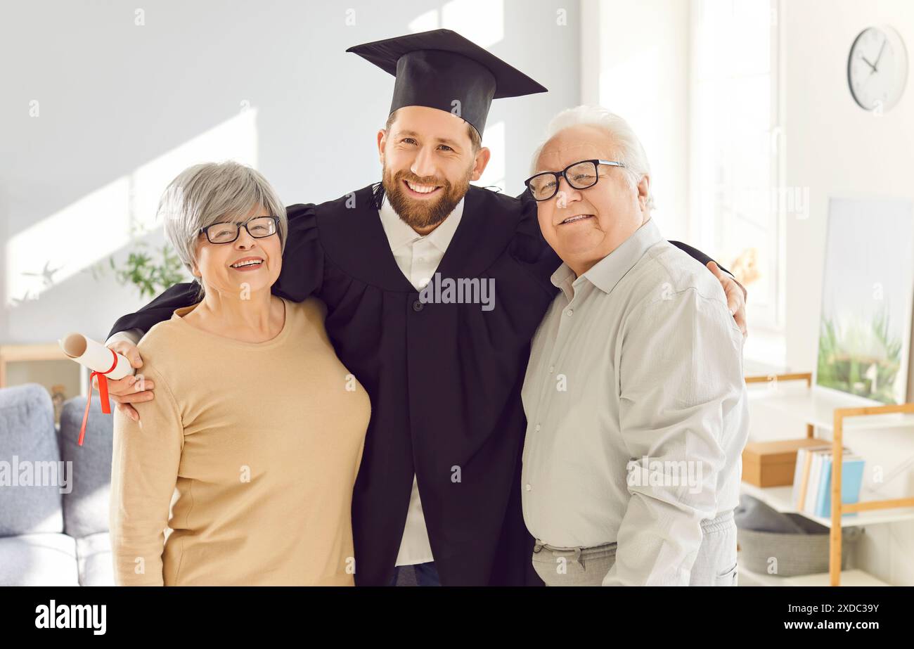 Graduating from university graduate in cap and gown hugging old parents ...