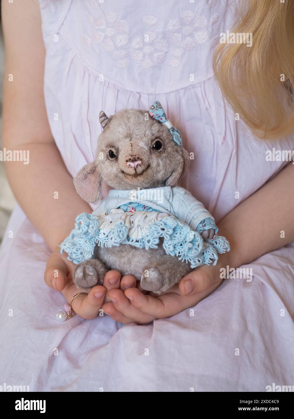 Handcrafted Teddy Lamb in Blonde Toddler Girl’s Hands Against a Pastel Pink Cotton Dress ...