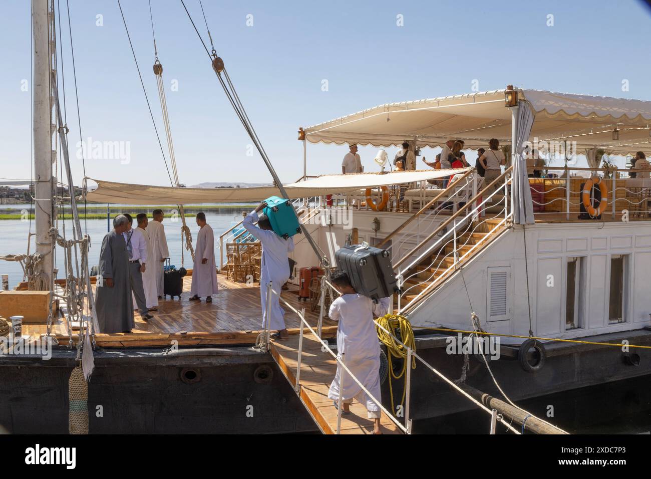 Gallibaya-clad porters take passengers' luggage aboard the Lazulil Nile ...