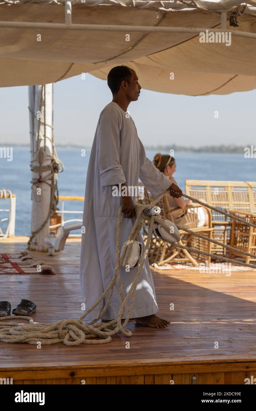 A gallibaya-clad sailor controls the rudder at the stern (rear) of a traditional two-masted ...