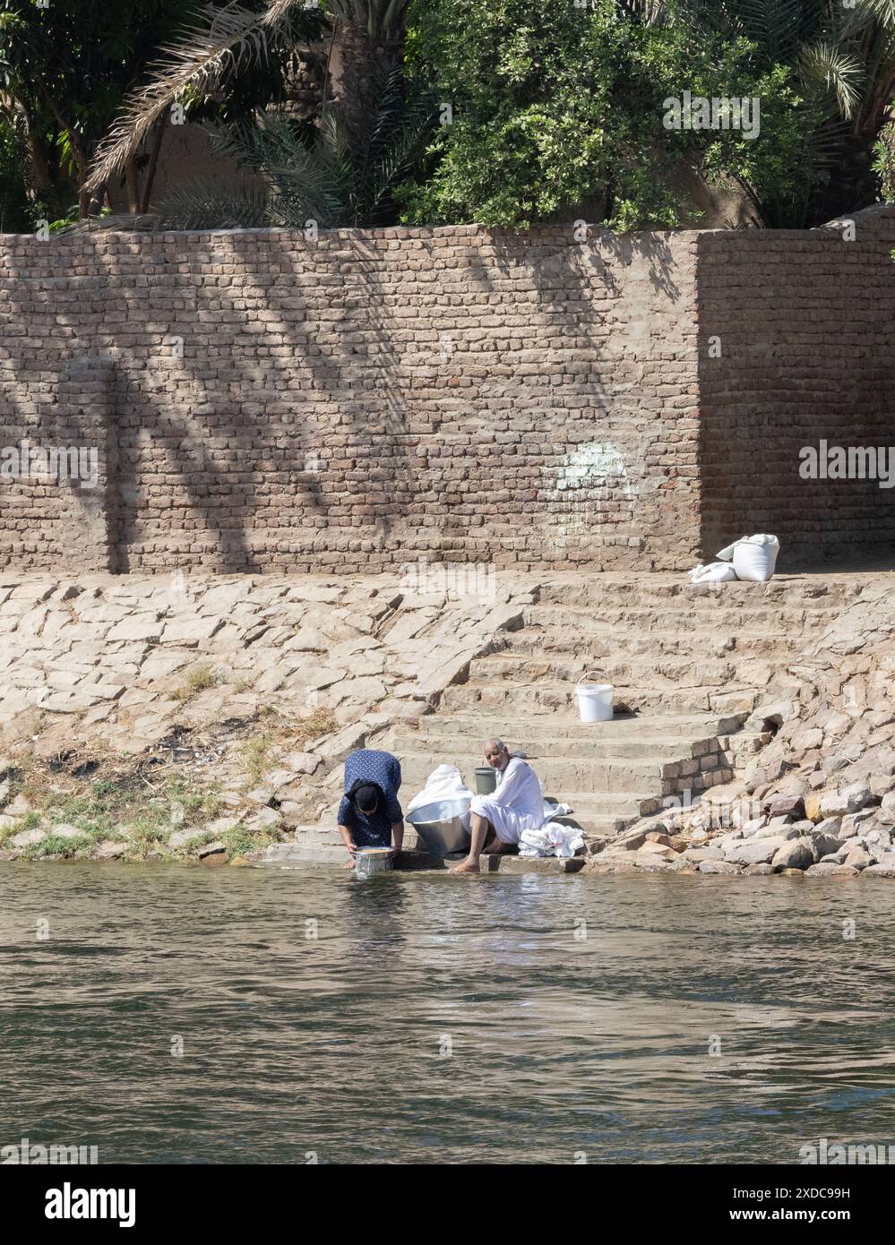 An elderly Egyptian couple in traditional dress do some washing-up in ...