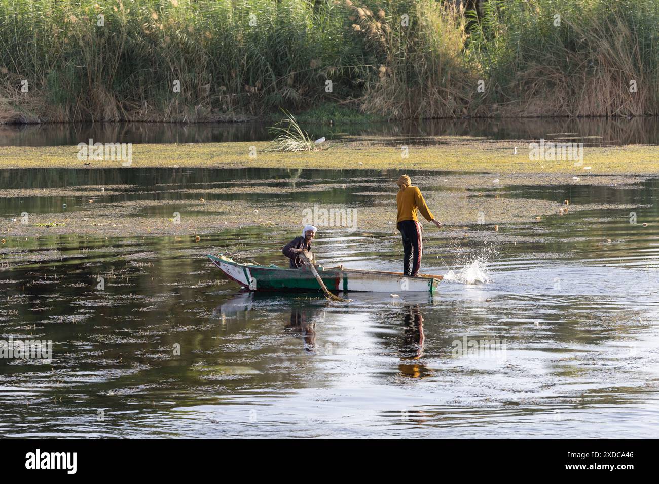 A smiling fisherman and his colleague fish in late afternoon on the ...