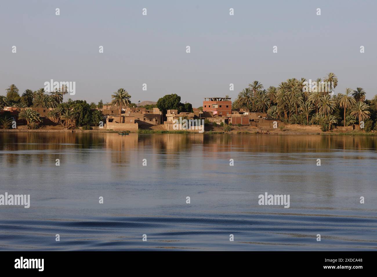 Two Egyptians row a traditional boat down the still waters of the Nile ...