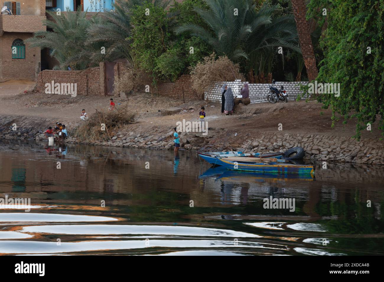 Egyptian women in colourful traditional clothing chat whilst children ...