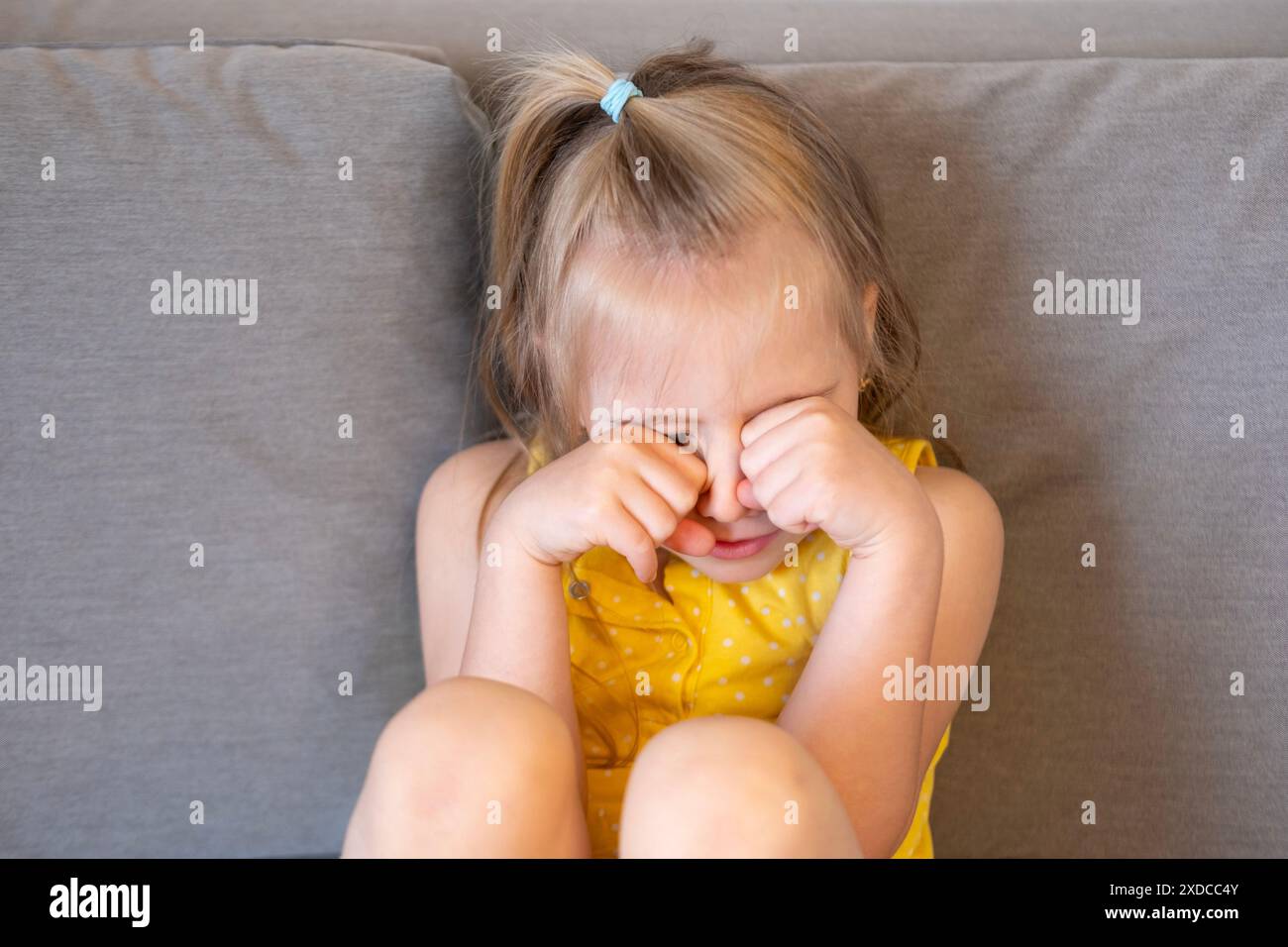 angry blonde girl in soft blurred video covers eyes with hands during ...