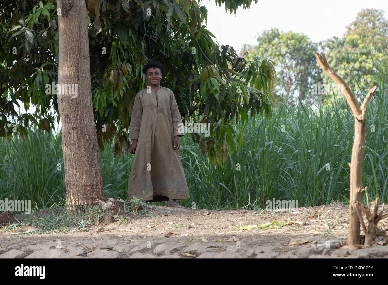A handsome Egyptian boy wearing a sweat-stained traditional gallibaya ...