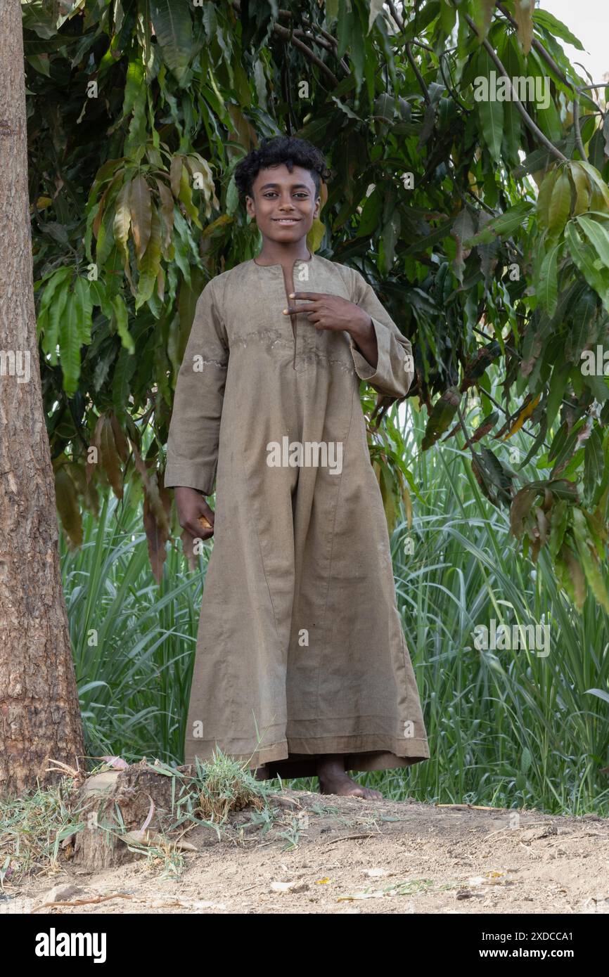 A handsome Egyptian boy wearing a sweat-stained traditional gallibaya ...