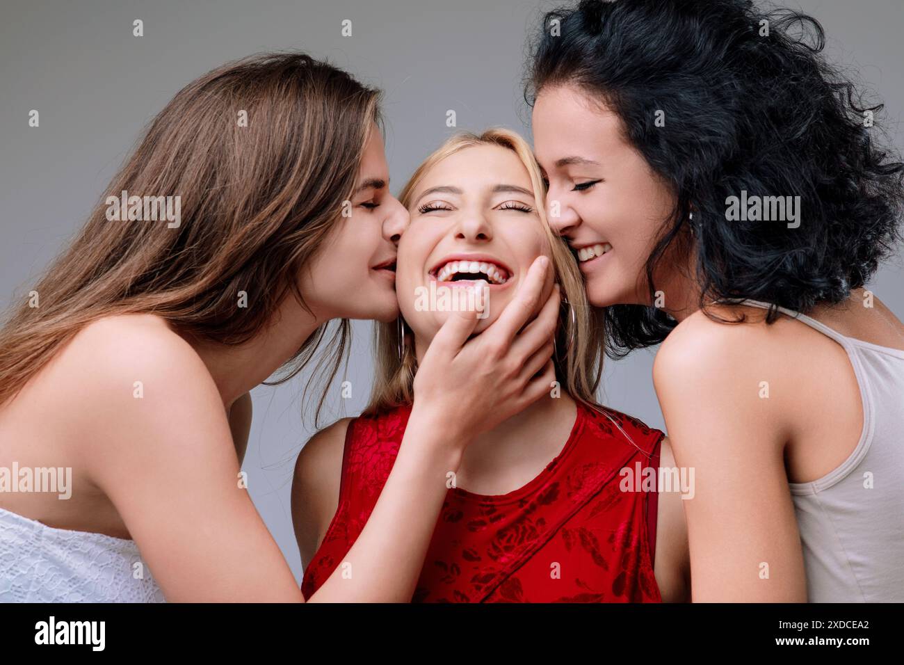 Three young women joyfully laugh and show affection, radiating ...