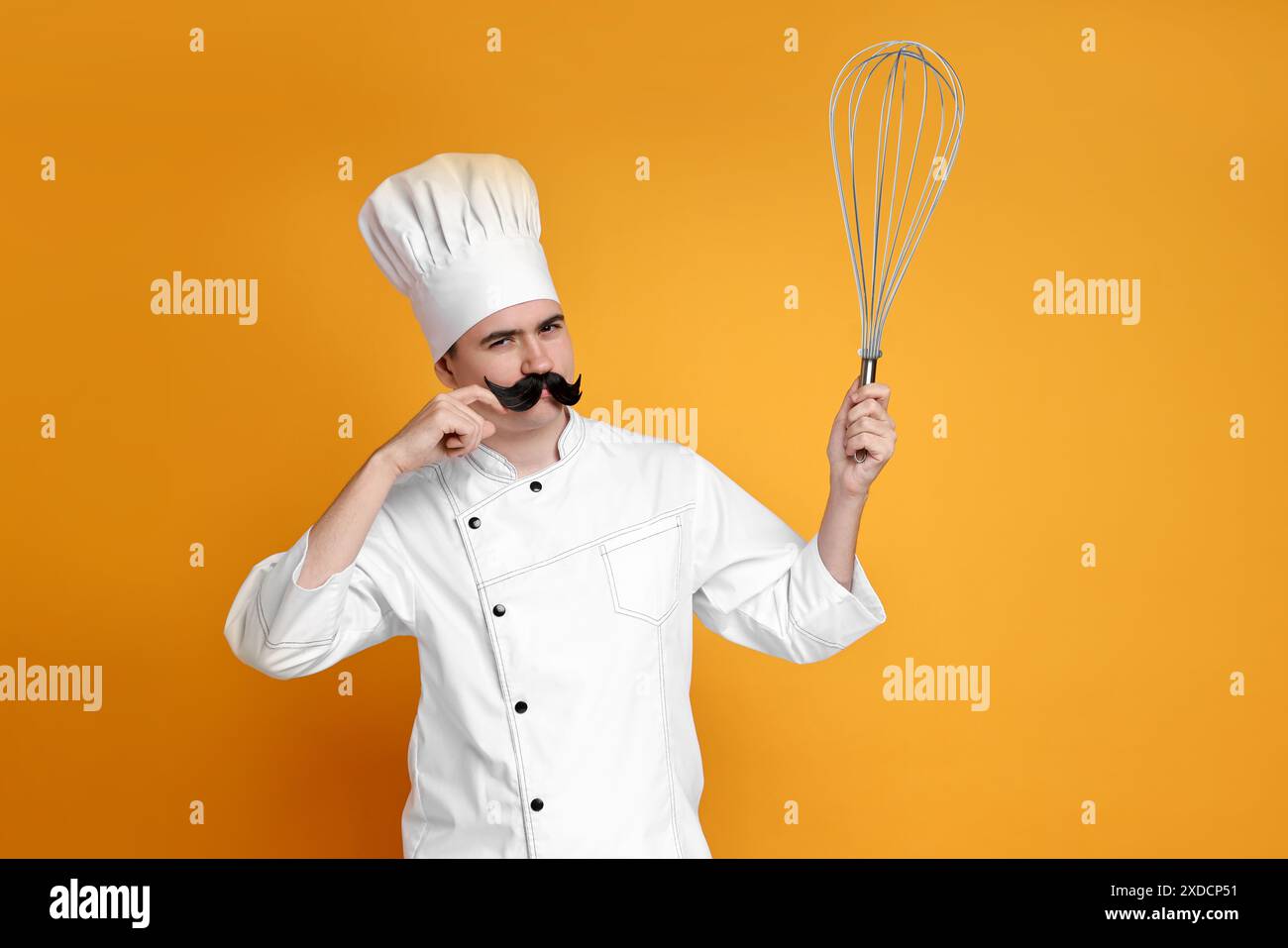 Pastry chef with fake mustache and big whisk on orange background Stock ...