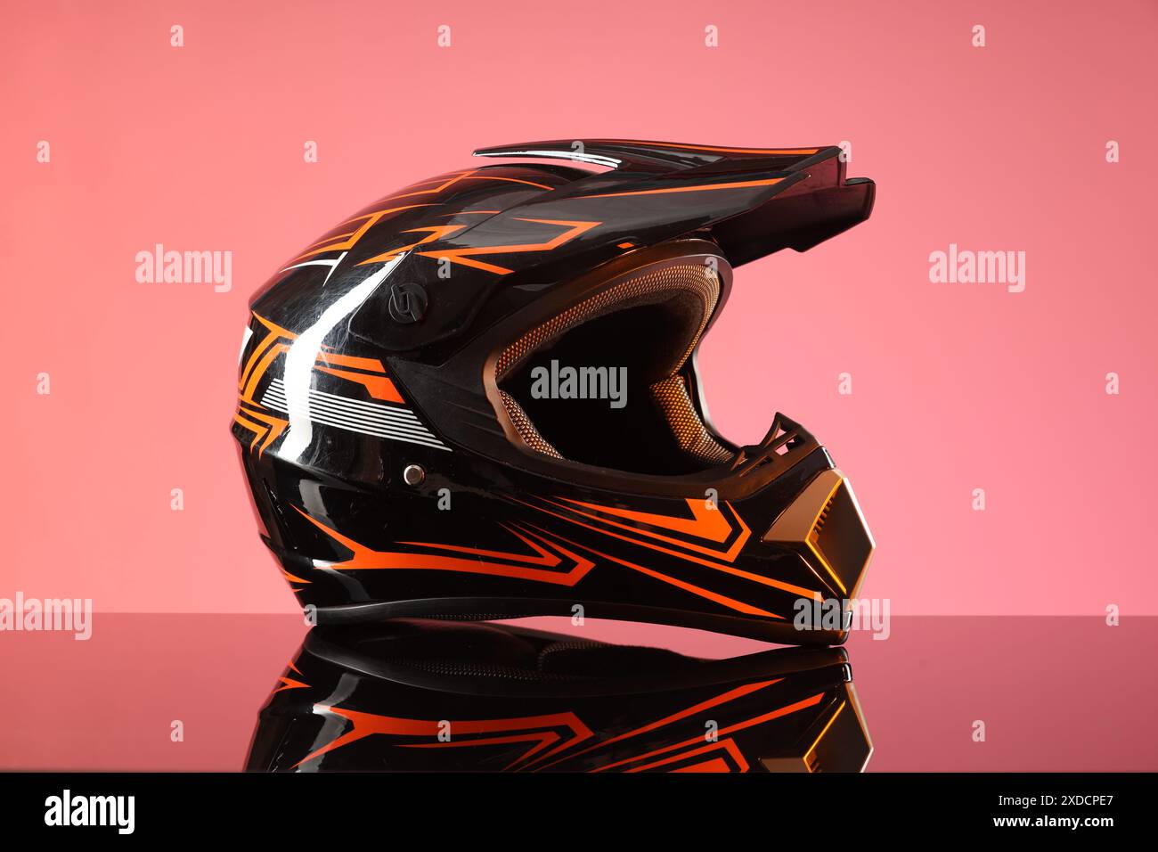 Modern motorcycle helmet with visor on mirror surface against pink ...