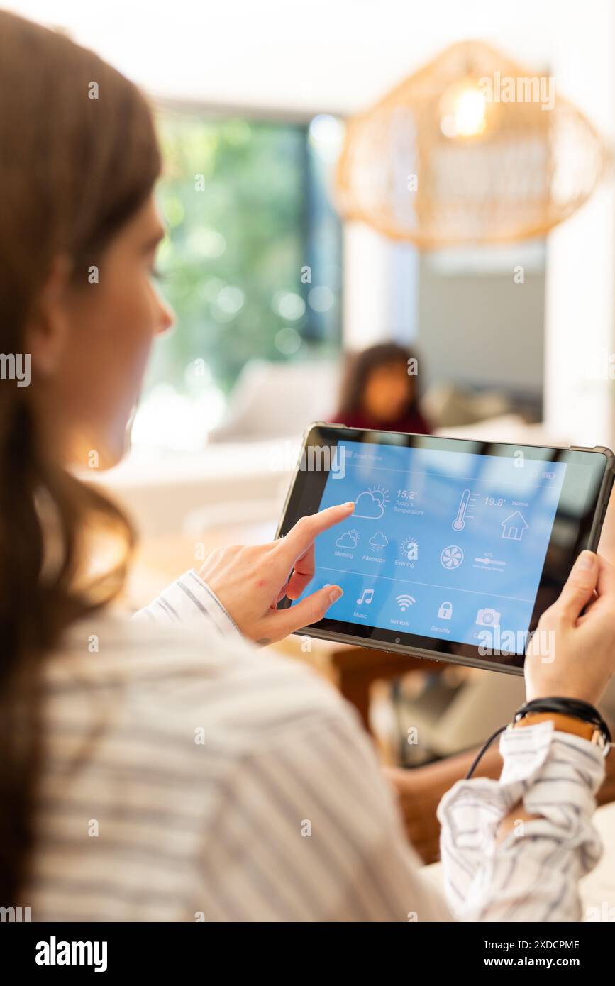 Using tablet, woman adjusting smart home settings in living room Stock ...