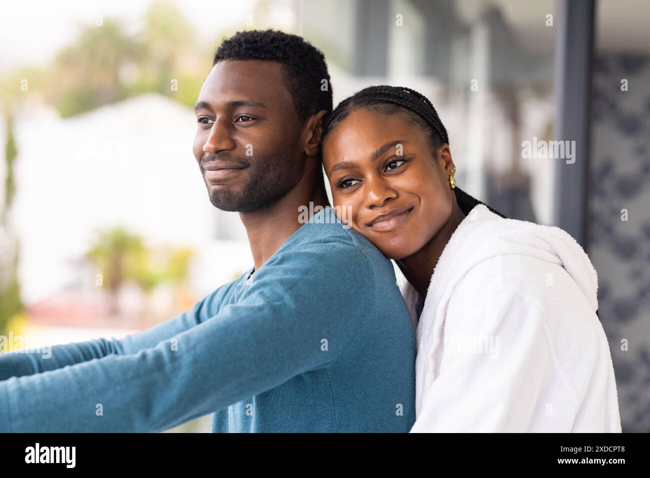 Young couple standing together at home, woman hugging man from behind ...