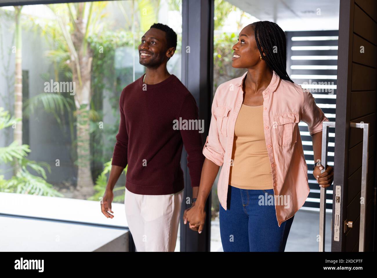 Holding hands, smiling, young Black couple entering home together Stock ...