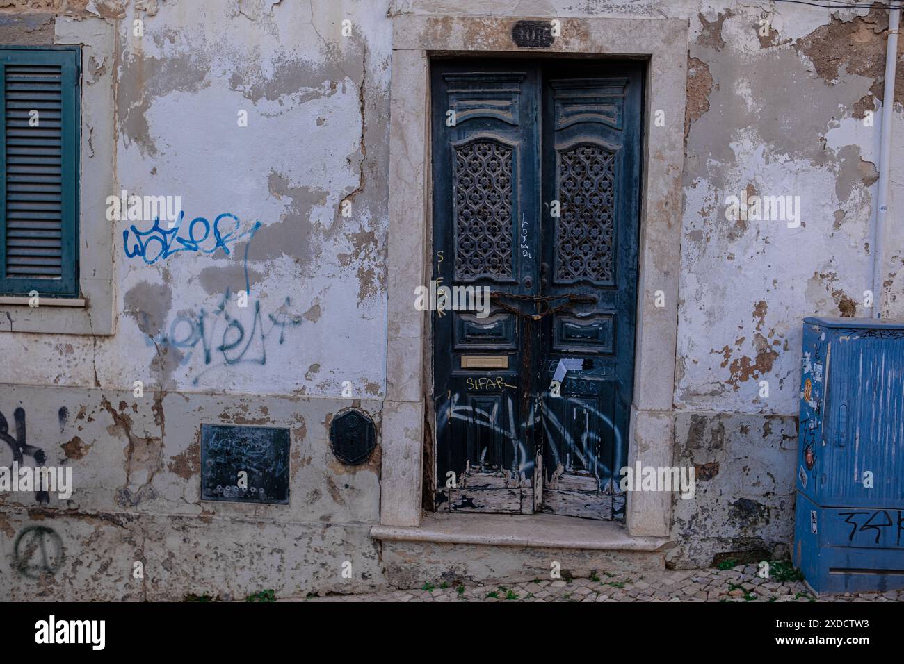 The locked and chained doors of an abandoned building are covered in ...