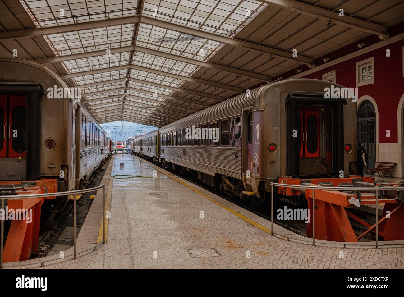 Modern passenger trains stand under the roof of a railway station in ...