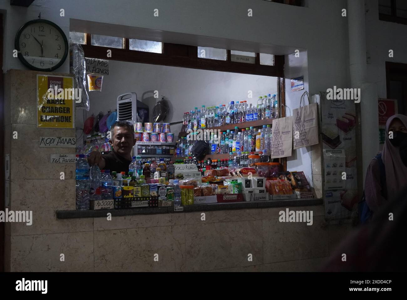 An old man was selling snacks at his booth at a station in the dark in ...