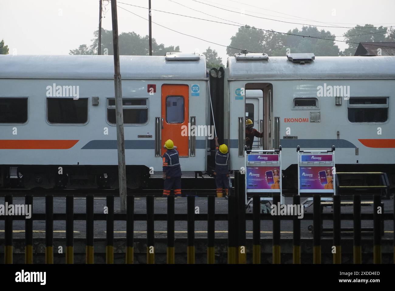 Workers at a train station in Indonesia cleaning the train body in the ...