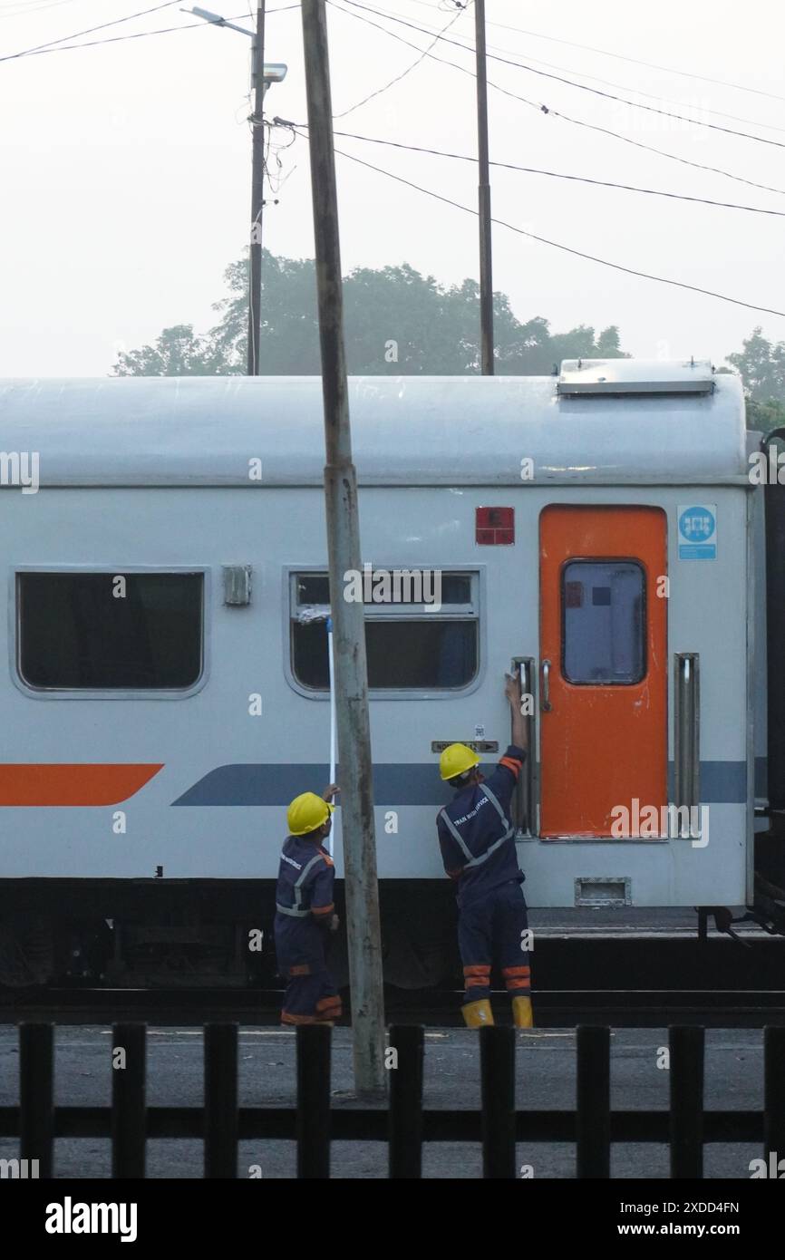 Workers at a train station in Indonesia cleaning the train body in the ...