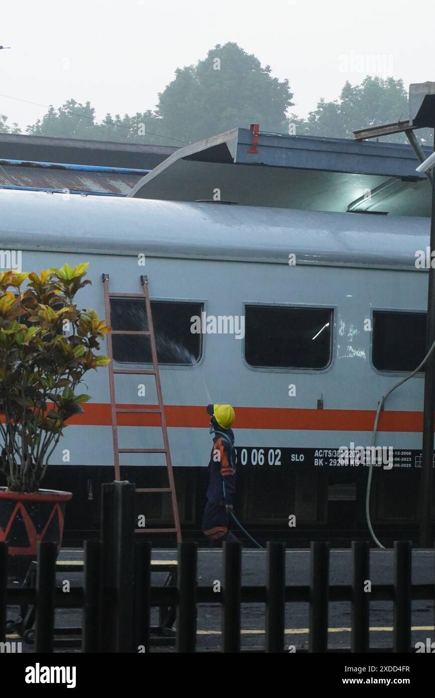 Workers at a train station in Indonesia cleaning the train body in the ...