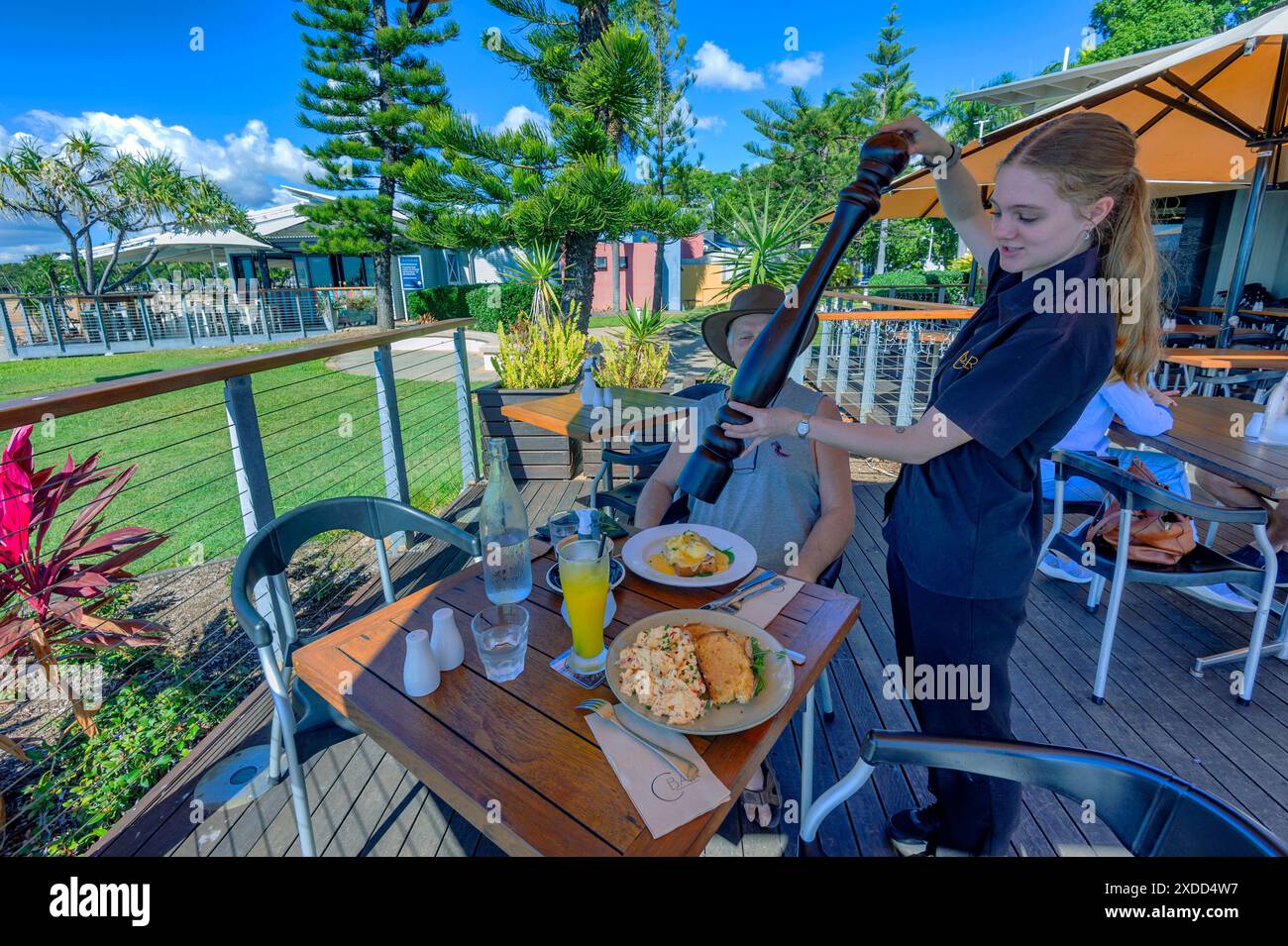 Pretty young waitress using a giant pepper mill at the C-Bar, a popular seaside restaurant ...