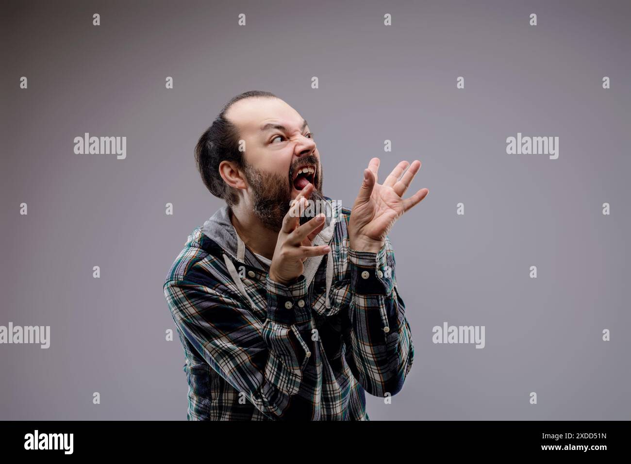 Bearded man screams angrily, gesturing wildly with hands, showing signs ...