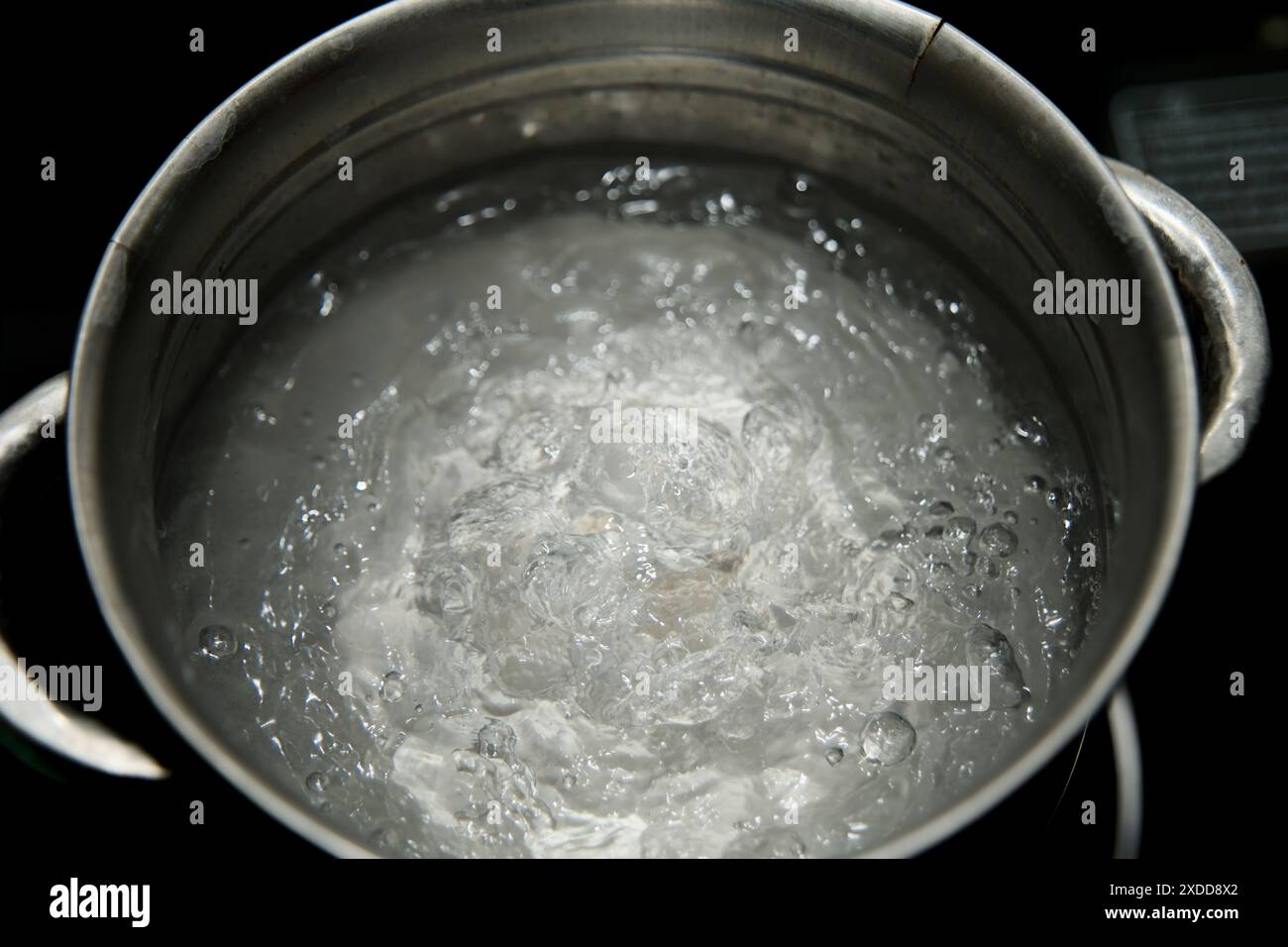 A stainless steel pot filled with boiling water sits on a gas stove ...