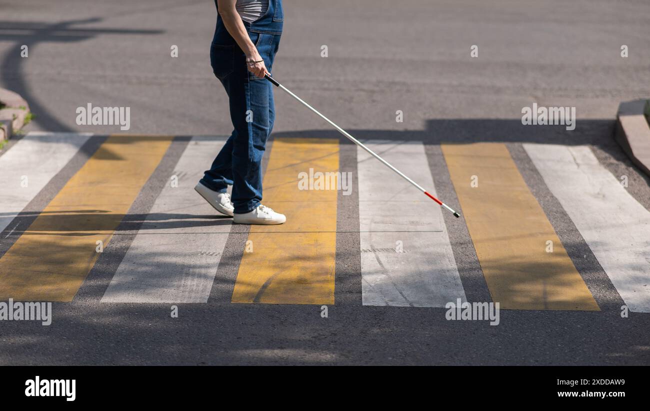 Close-up of the legs of a blind woman crossing the road at a crosswalk ...