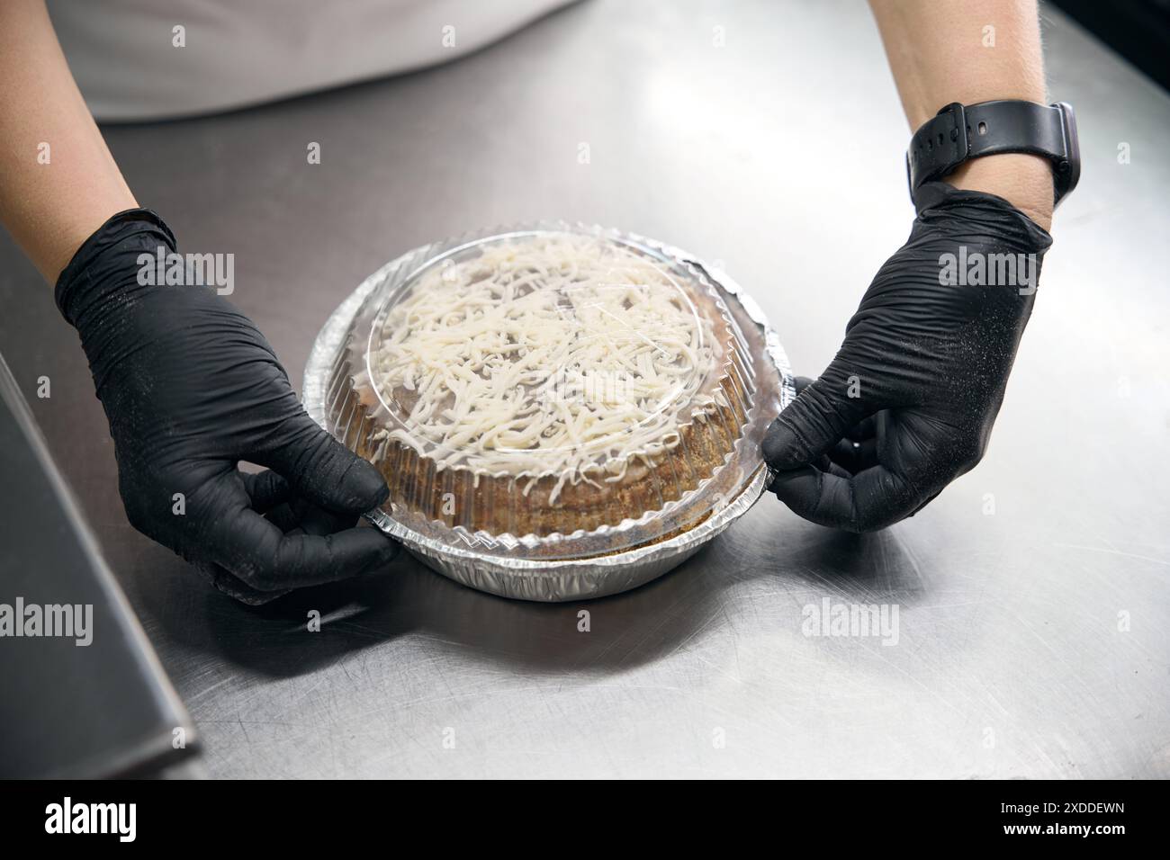 Employee of the semi-finished products workshop packs a meat pie Stock ...