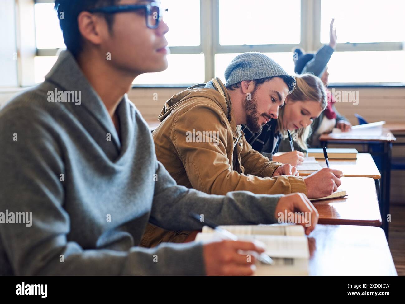 University students, writing and desk in classroom with books for ...