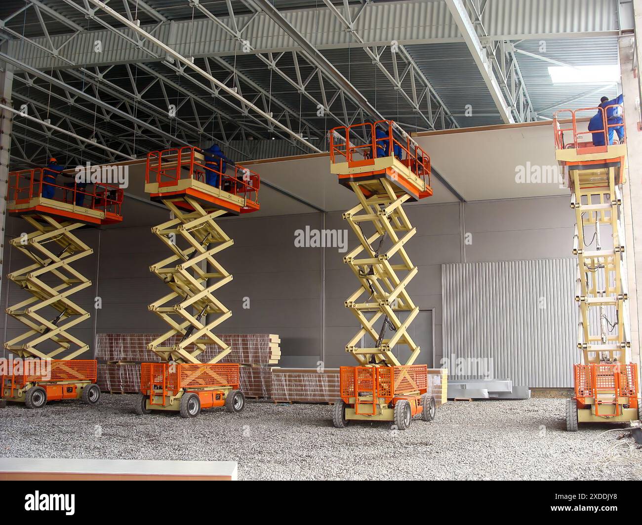 Workers installing PIR sandwich panels using scissor lifts inside a ...