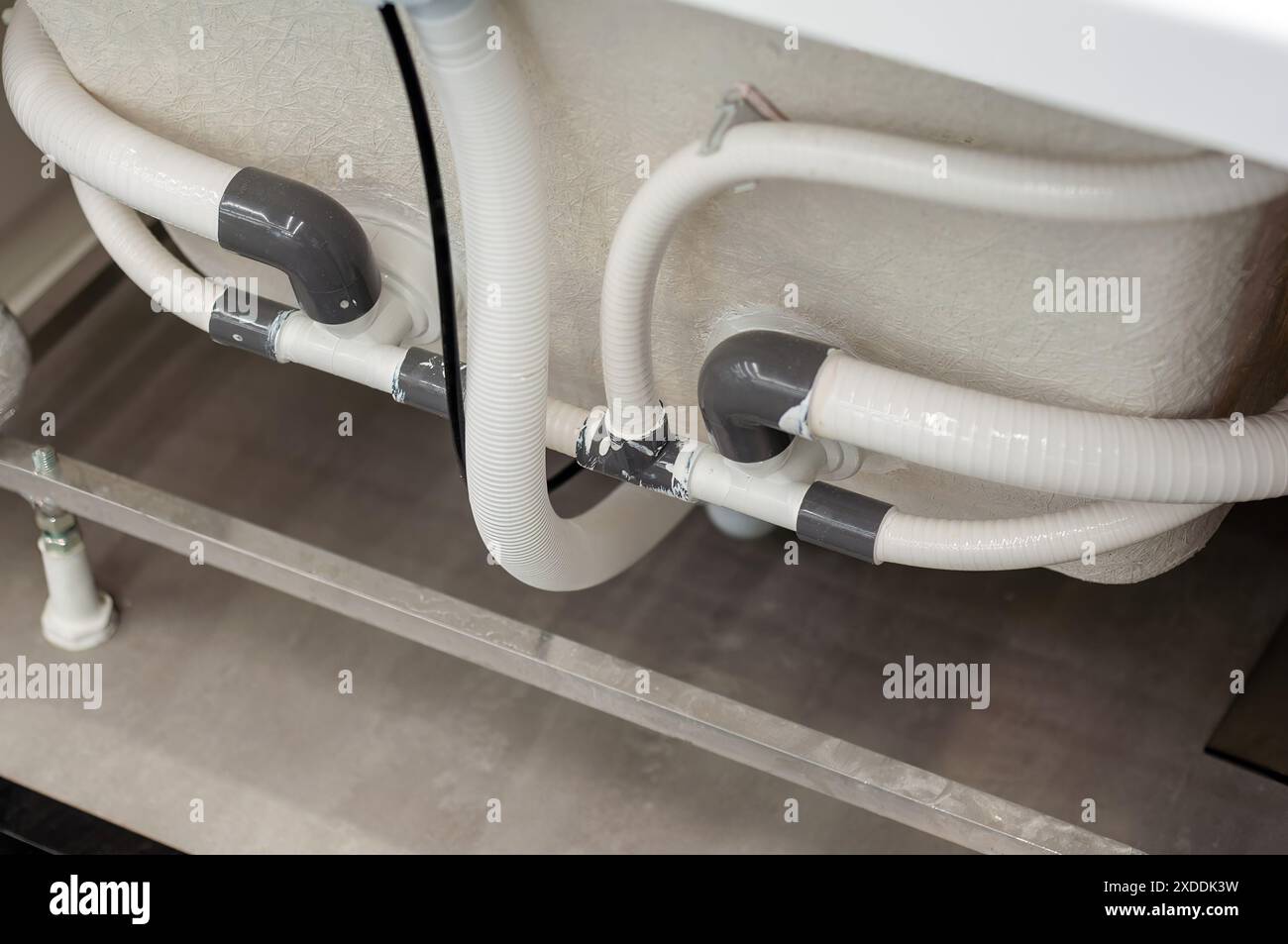 Close-up view of plumbing pipes and connections under an acrylic ...