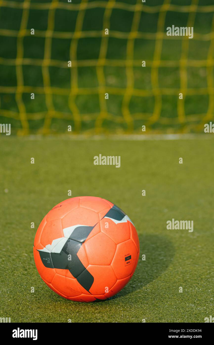 red soccer ball with the yellow net of a goal on an artificial grass ...