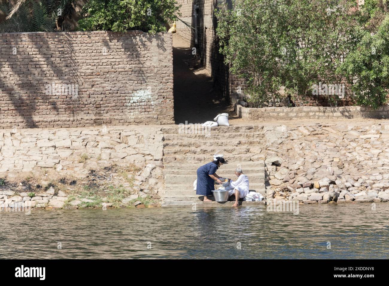 An elderly Egyptian couple in traditional dress do some washing-up in ...