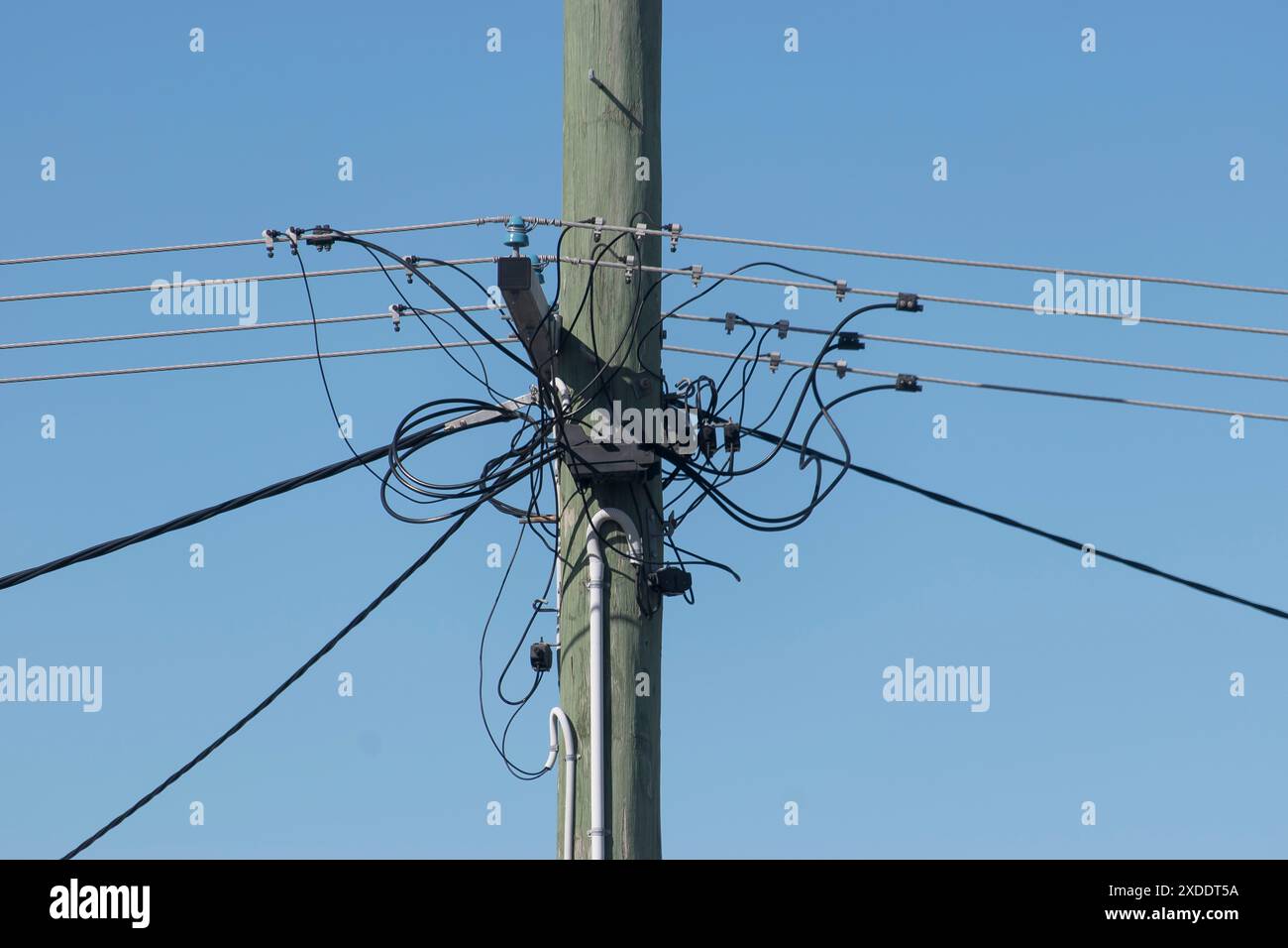 Confused mass of electrical connections on a power-pole beside road on ...