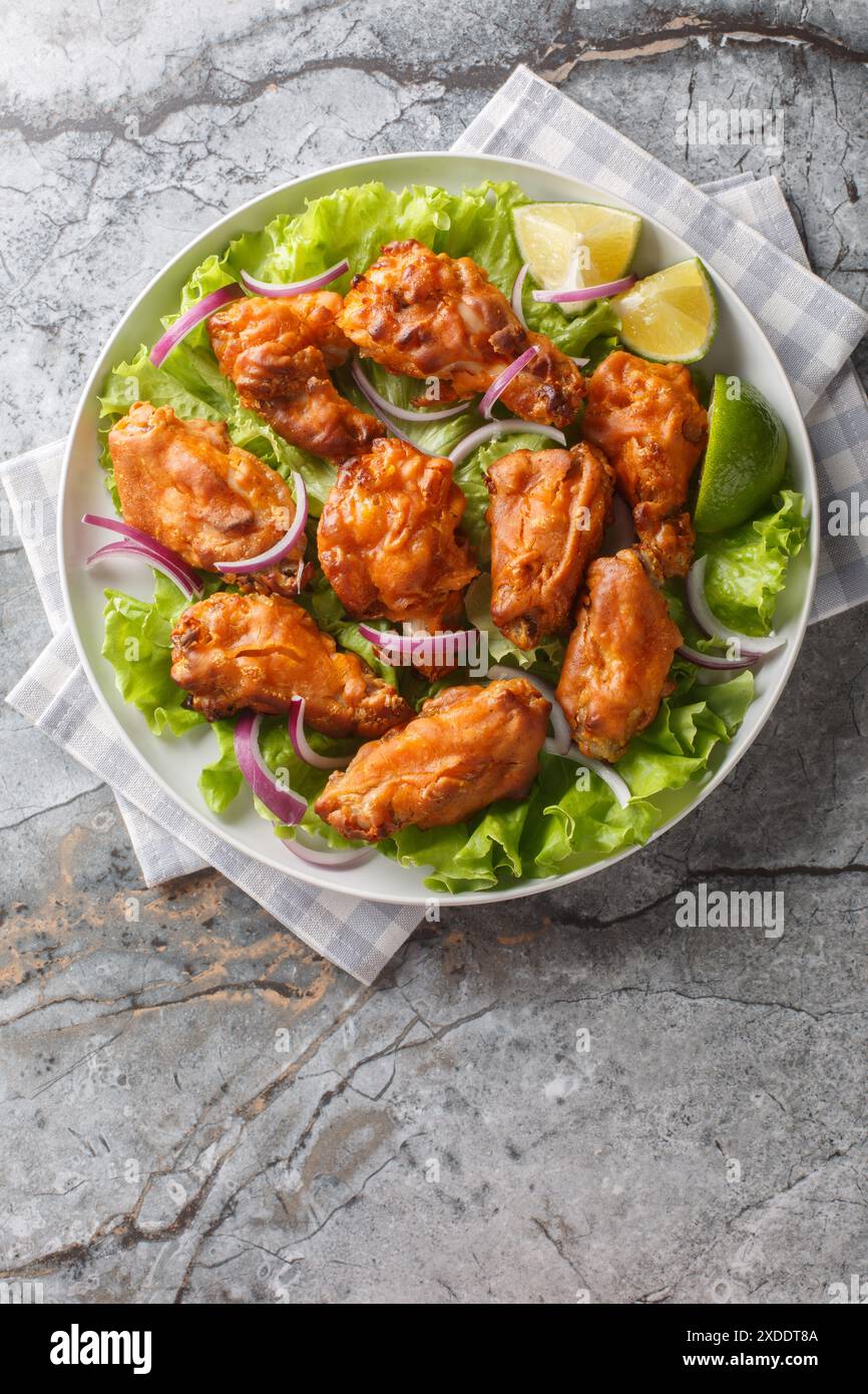 Thai Tom Yum Chicken served with onion, lime and lettuce closeup on the ...
