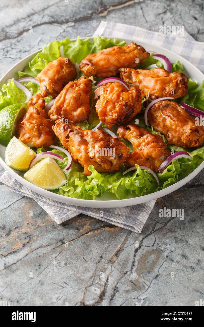 Thai Tom Yum Chicken served with onion, lime and lettuce closeup on the ...