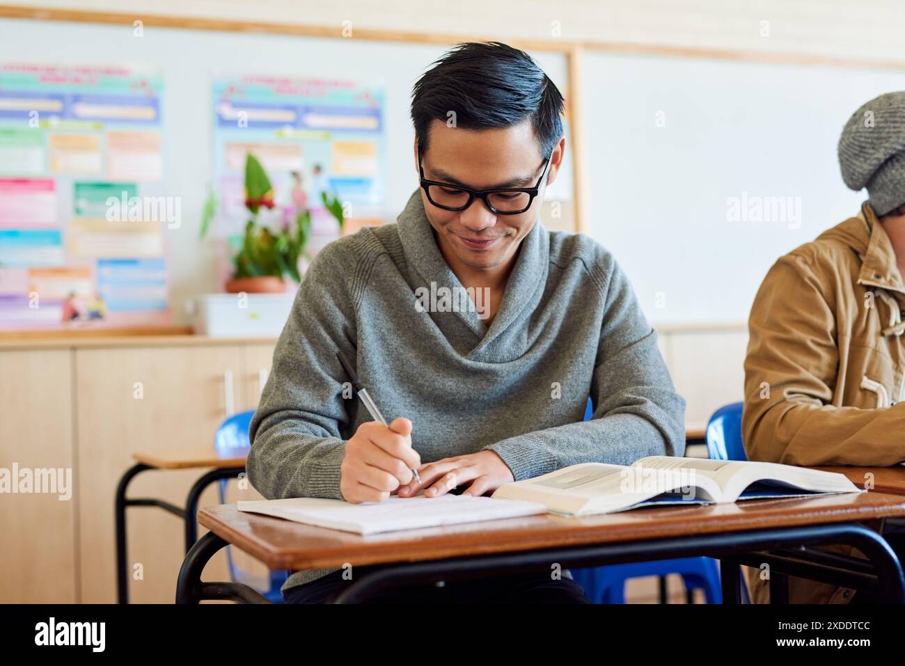 University student, man and writing in classroom with books for english ...