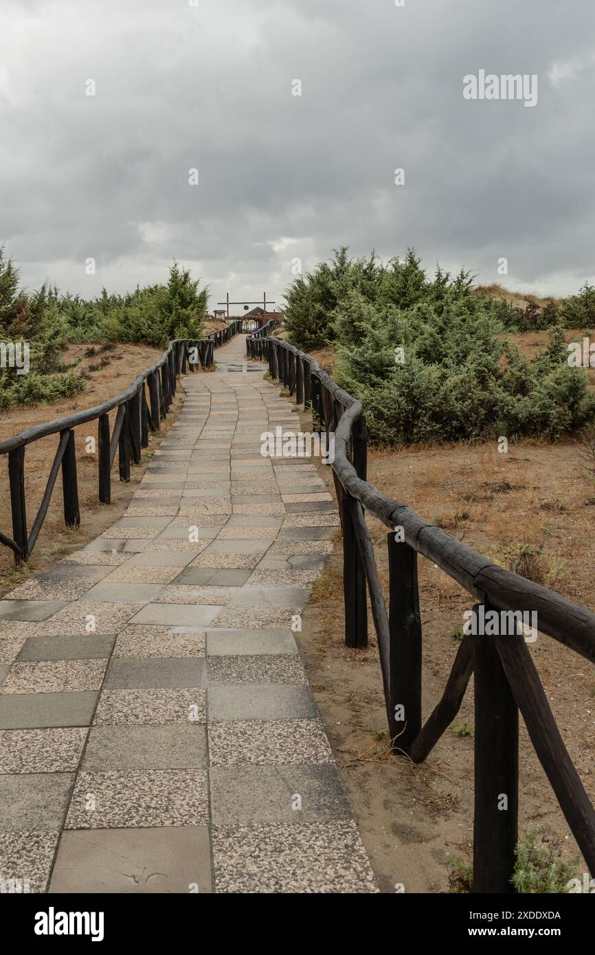 A stone pathway with wooden railings leading to the distant beach under ...