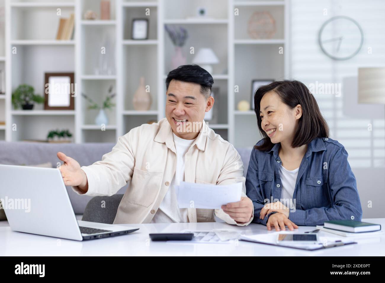 Young smiling Asian family, man and woman sitting at home at table in ...