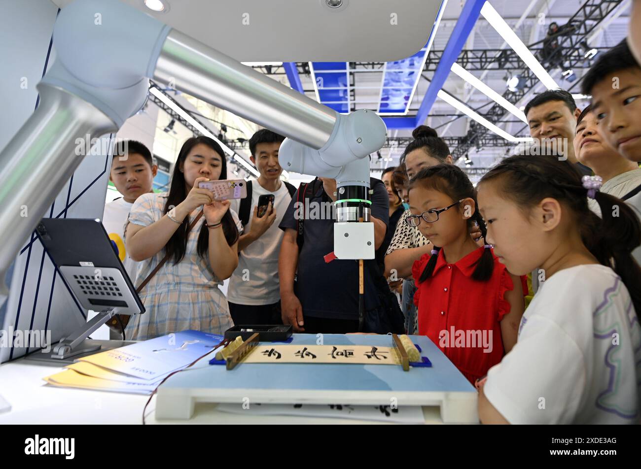 Tianjin. 22nd June, 2024. Visitors watch as a robot writes Chinese ...